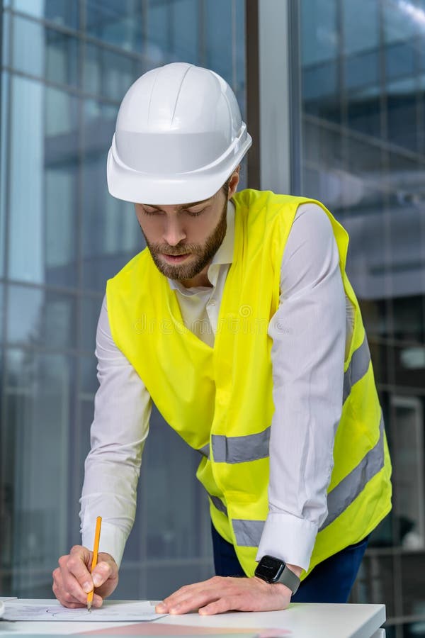 Male Engineer in a Yellow Vest and Card Cap Working in the Office Stock ...