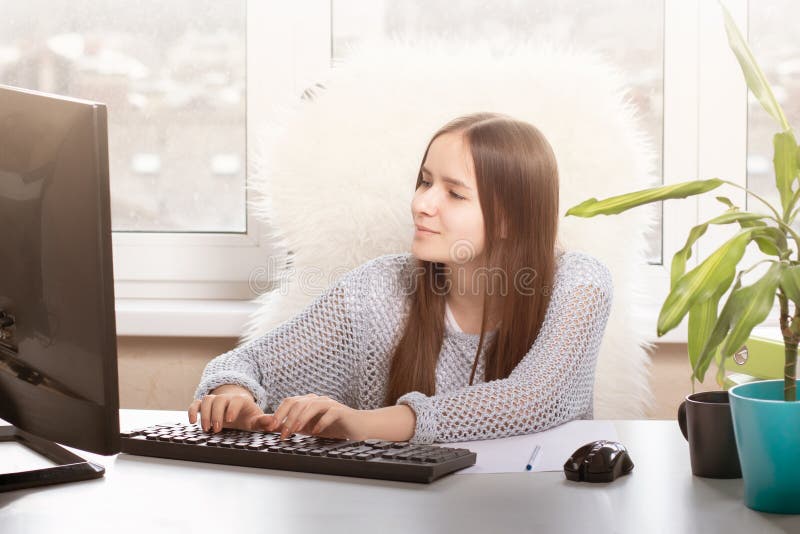 Work in the Office. a Young Girl Sits at a Table Typing on a Computer ...