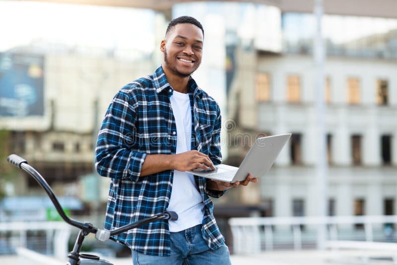 Black Man Using Laptop, Standing in Downtown with Bike Stock Photo ...