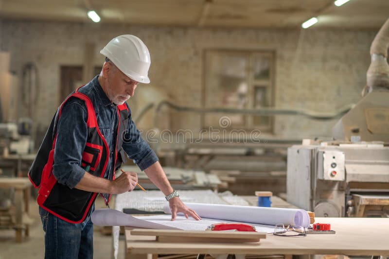 Man in Protective Helmet Working in a Workshop with Drawings Stock ...