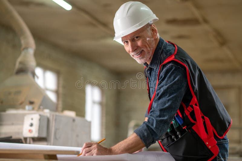 Mature Man in Protective Helmet Working in a Workshop and Looking ...