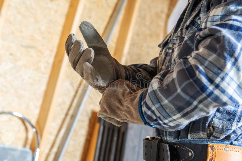 Worker Adjusts Gloves in a Workshop while Preparing for a Construction ...