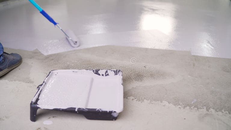 A Worker Applies White Paint with a Roller. Application of Paint with a ...