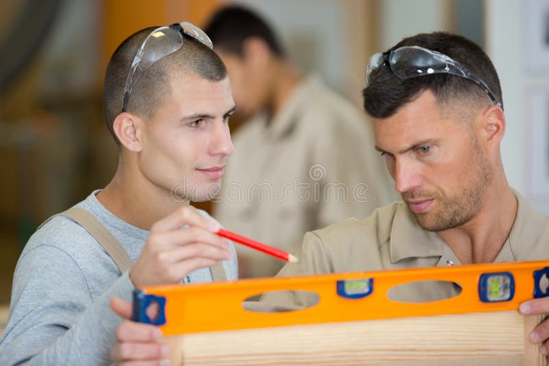 Worker with Apprentice Looking at Level Stock Photo - Image of foreman ...