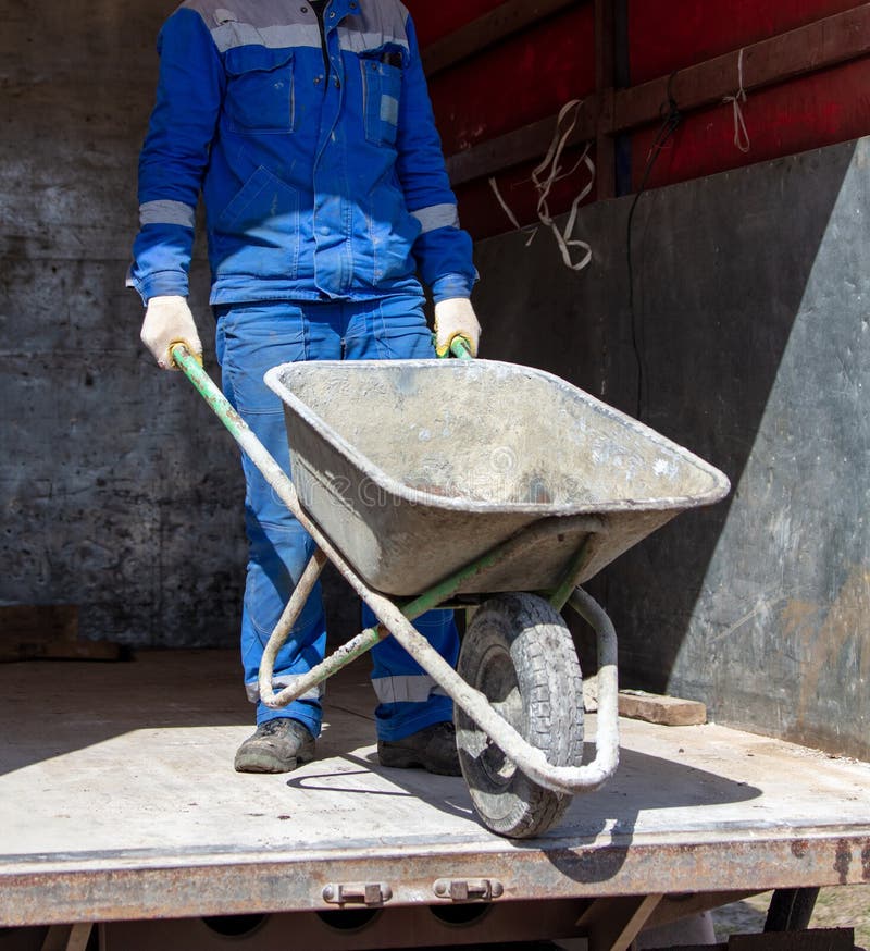 Worker in Blue Clothes with a Wheelbarrow in His Hands Stock Image ...