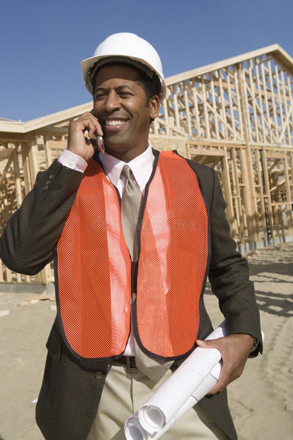 Worker with Blueprints Using Cell Phone at Construction Site Stock ...