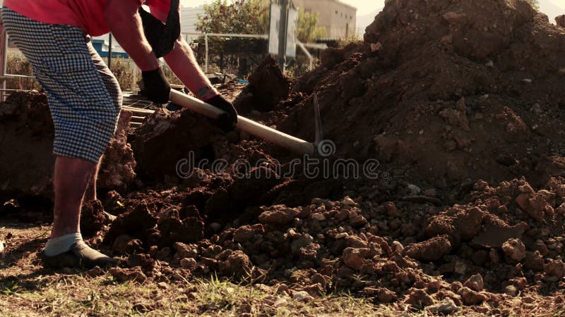 A Worker Breaks Up a Pile of Dirt with a Pick Stock Footage - Video of ...