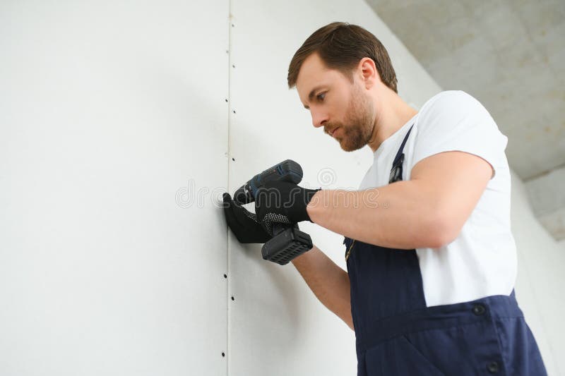 Worker Builder Installs Plasterboard Drywall at a Construction Stock ...