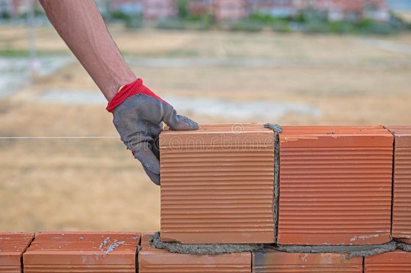 Worker Builds a Brick Wall for House Construction. Worker Building a ...