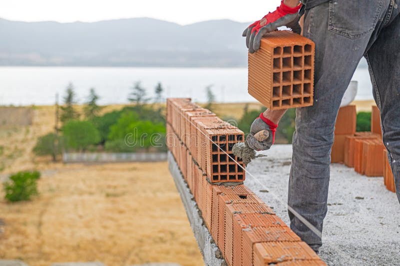 Worker Builds a Brick Wall for House Construction. Worker Building a ...