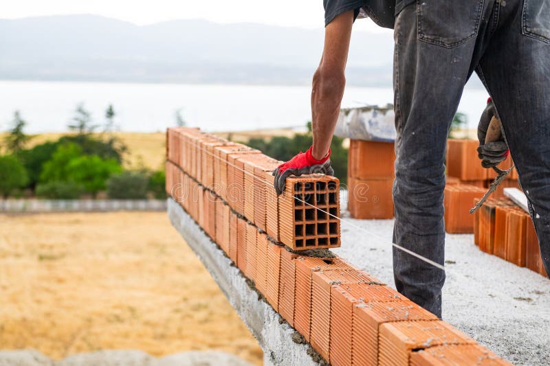 Worker Builds a Brick Wall for House Construction. Worker Building a ...