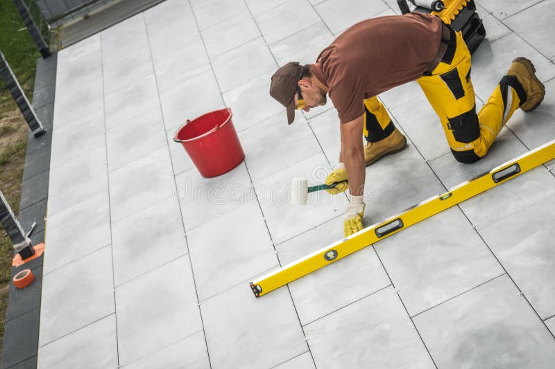A Worker Carefully Lays Tiles Using a Level Tool on a Clean Outdoor ...