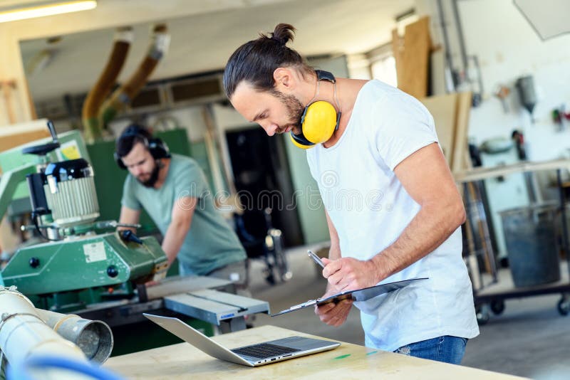 Worker in a Carpenter`s Workshop with Computer and Clipboard Stock ...