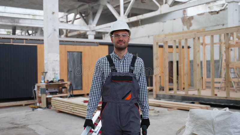 Worker Carpenter in Uniform Walks with Tools Near Unfinished ...