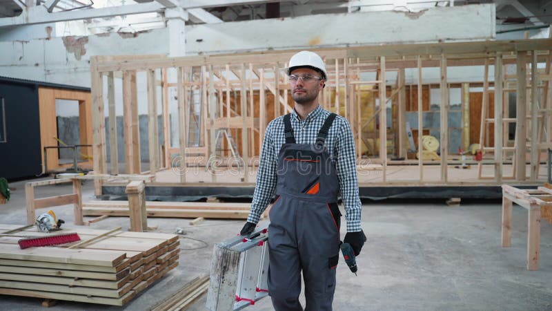 Worker Carpenter in Uniform Walks with Tools Near Unfinished ...