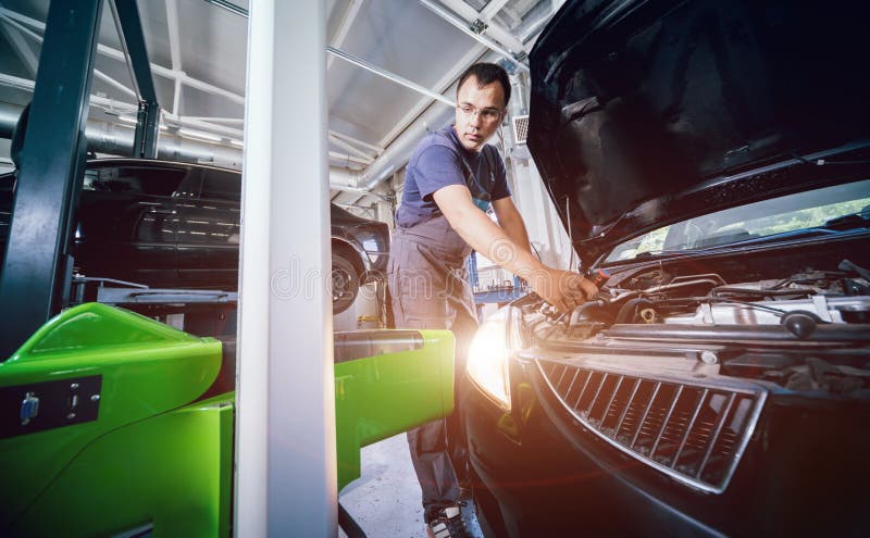 Worker Checks and Adjusts the Headlights of a Car`s Lighting System ...