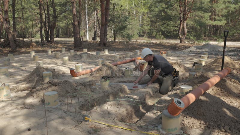 Construction Worker Laying Underground Pipes in a Forested Area during ...