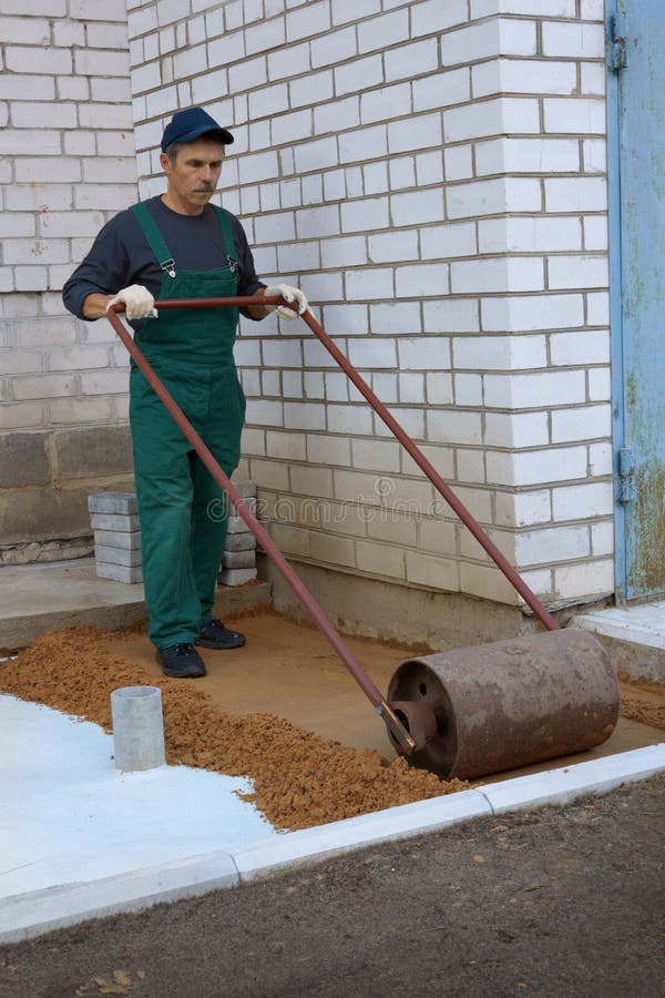 Worker Compacts Soil with a Hand Roller before Construction of Sidewalk ...