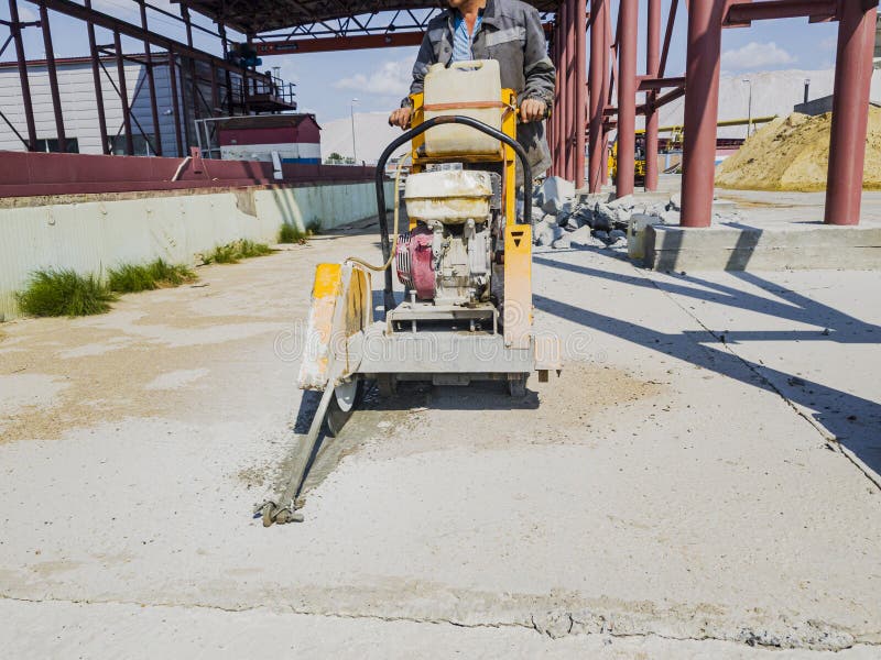 A Worker at a Construction Site Cuts Concrete with a Diamond Saw ...