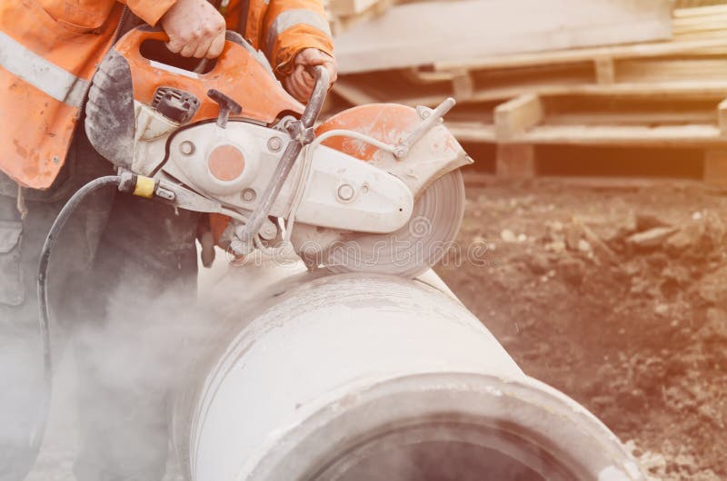 Worker at the Construction Site Cutting a Concrete Drainage Pipe with a ...