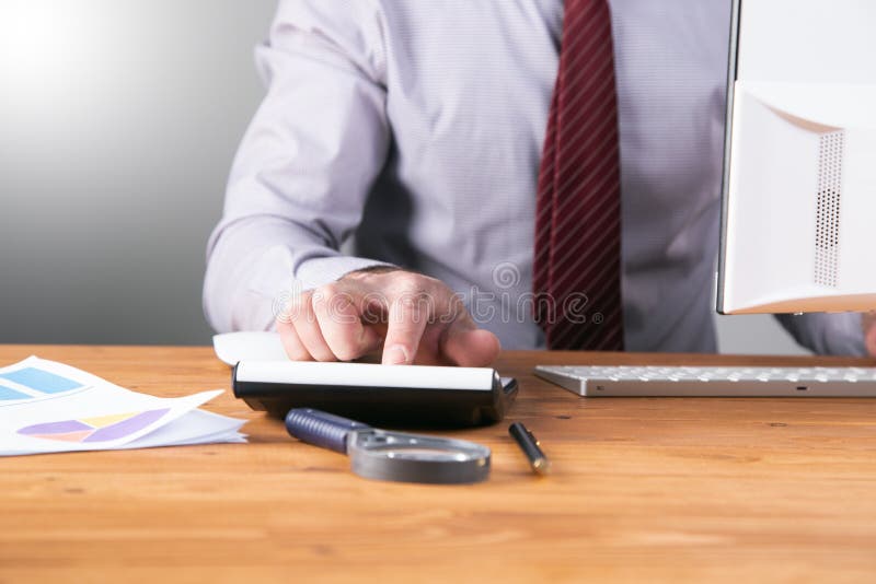 Worker is Counting on a Calculator Sitting at His Desk Stock Photo ...