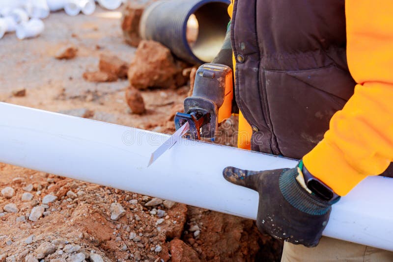 Worker Cuts a Pipe on a Construction Site while Wearing Gloves and a ...