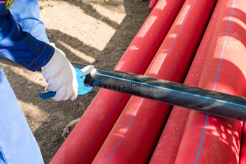 Worker Cuts a Plastic Pipe with Special Scissors at a Construction Site ...