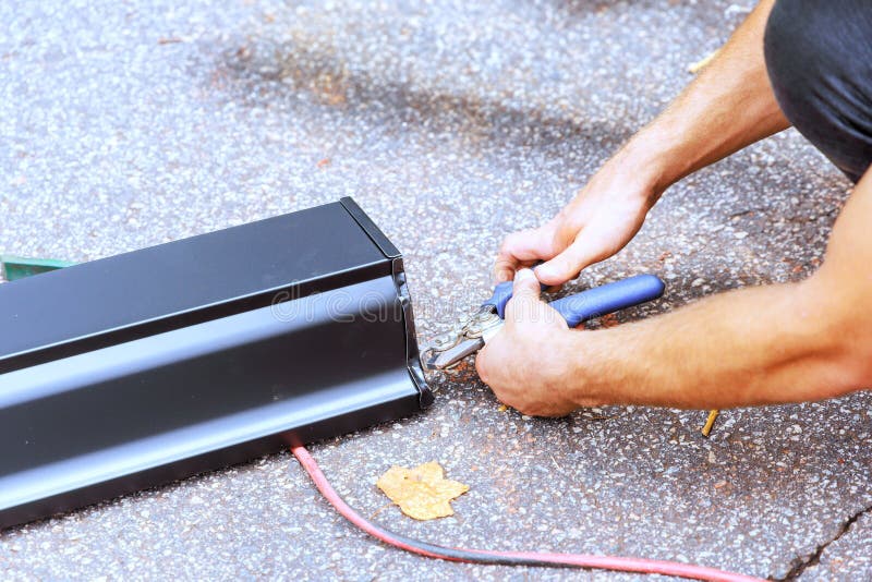 Worker Cutting Aluminum Rain Gutter with Shears after Bending at a ...