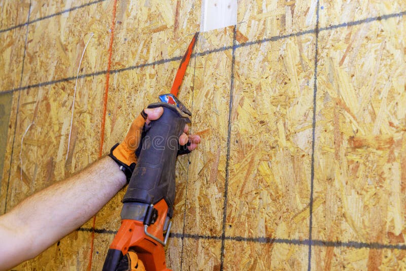 Worker Cutting into Oriented Strand Board To Install Insulation in a ...