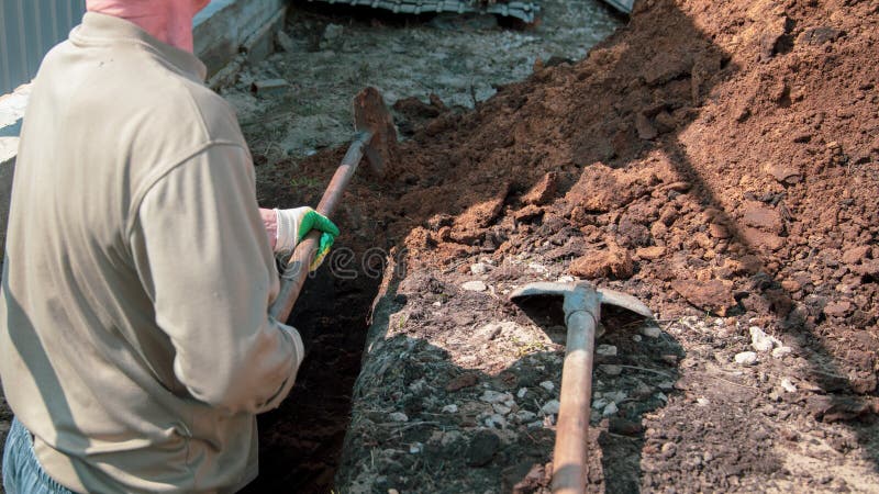 A Worker Digs a Pit with a Shovel on a Construction Site Stock Photo ...