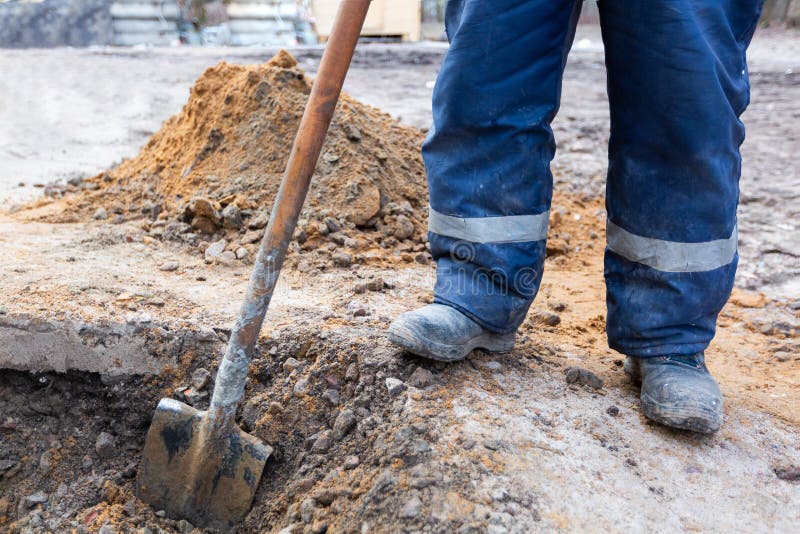 Worker in Dirty Uniform and Shoes with Shovel is Digging a Pit on ...