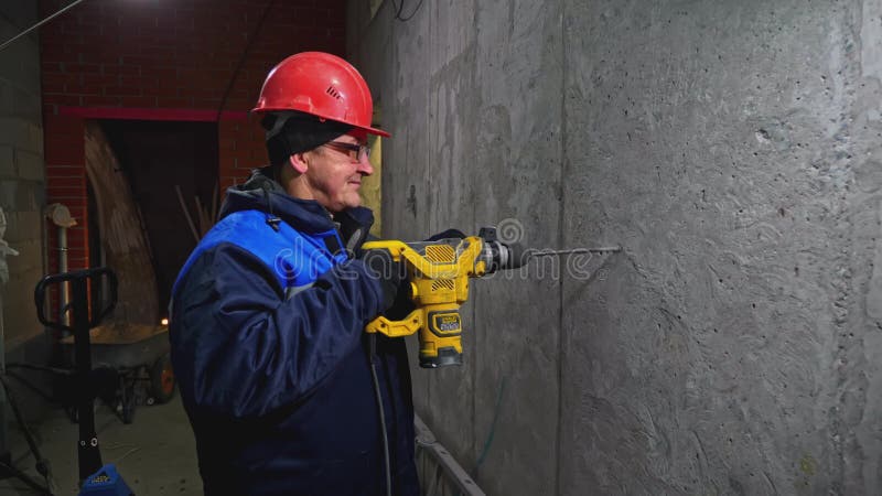 Worker Drills Concrete Wall with Screwdriver. Clip. Uniformed Worker ...