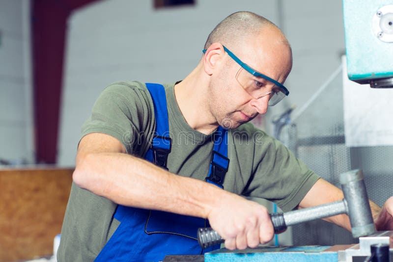 Worker in Factory on Work Bench with Hammer Stock Photo - Image of ...