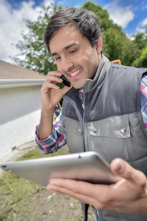 Worker in Garden on Telephone Holding Tablet Stock Image - Image of ...