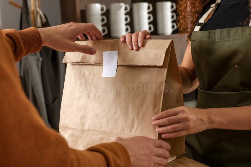 Worker Giving Paper Bag To Customer in Cafe, Closeup Stock Photo ...