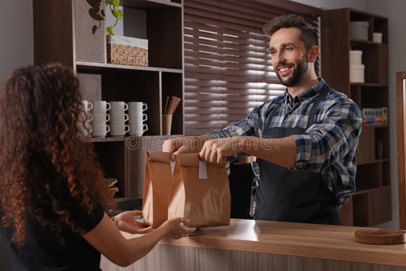 Worker Giving Paper Bags To Customer in Cafe Stock Photo - Image of ...