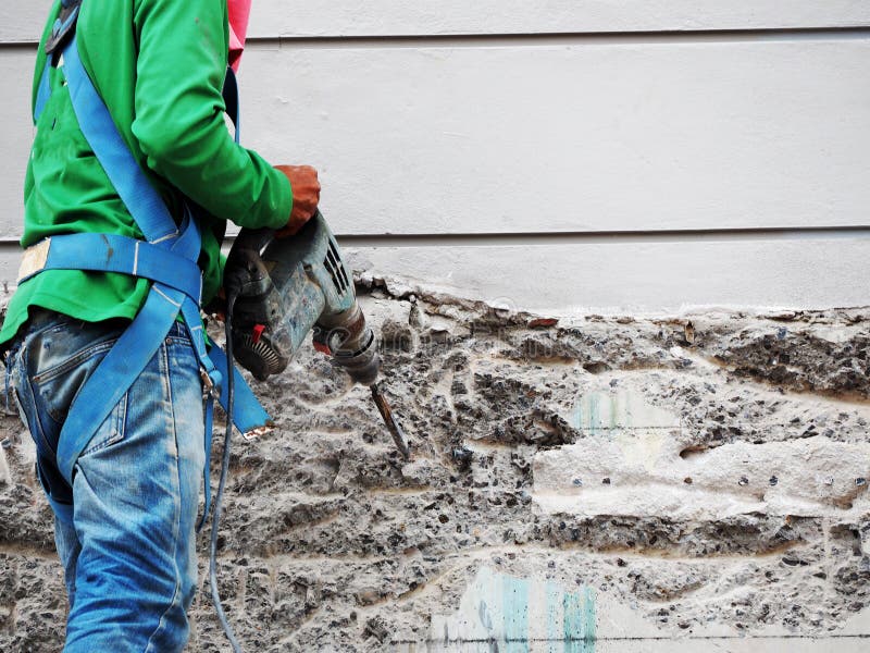 The Man Grinds the Concrete Wall.Grinding the Walls with a Drill and an ...