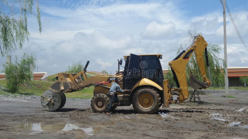 Worker and Heavy Equipment Backhoe in Construction Site Under Blue Sky ...