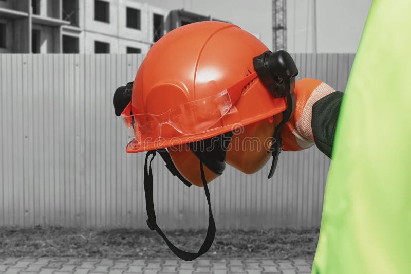 Worker in a High-visibility Vest Holds an Orange Hard Hat with Safety ...