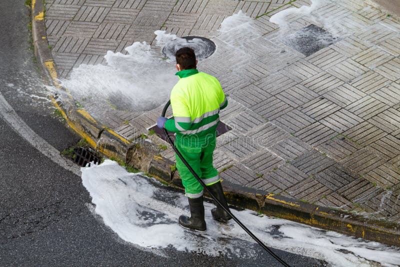 Worker Holding a Hose Cleaning the Sidewalk with Water and Detergent ...