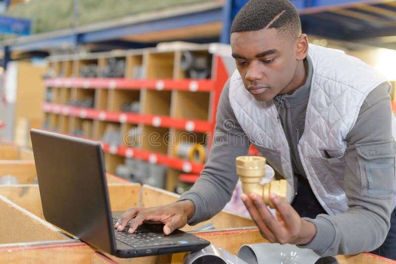 Worker Holding Pipe Fitting and Researching on Computer Stock Photo ...