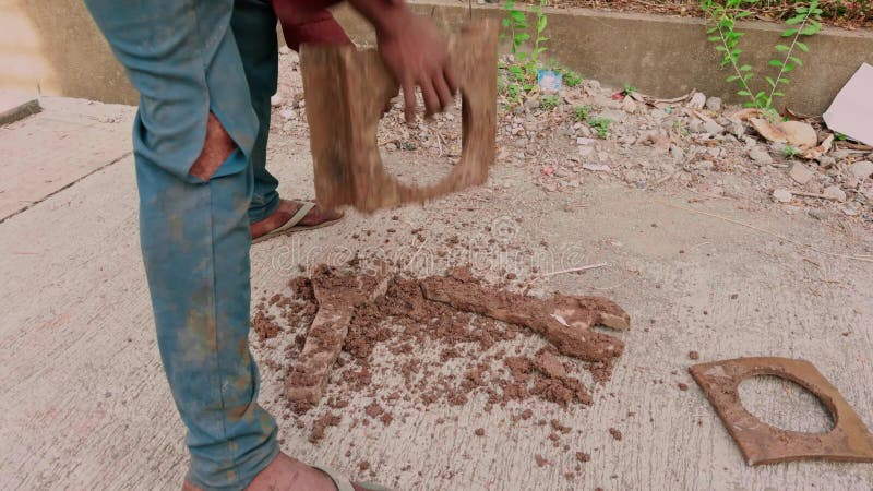 Worker Holding a Rusty Metal Part at a Construction Site with Debris on ...