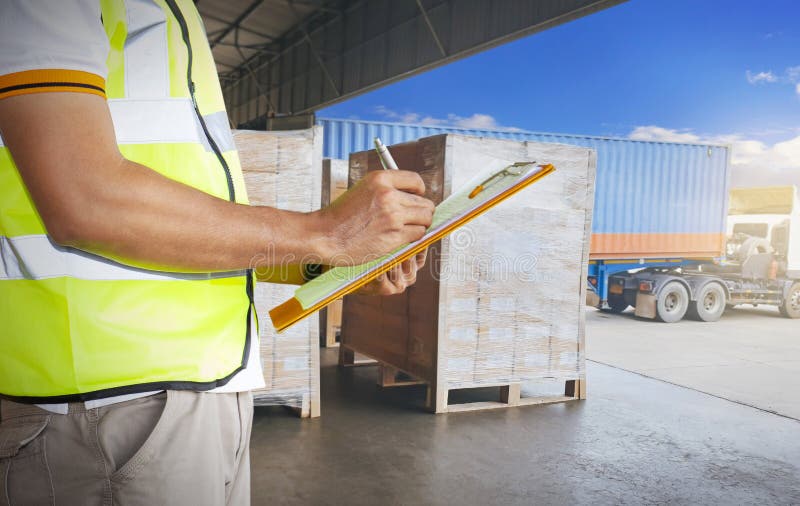Worker Holds a Clipboard Controlling the Loading of Cargo into Shipping ...