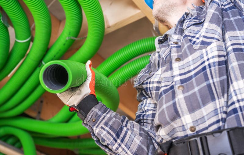 Worker Holds Green Hose in Workshop Surrounded by Similar Equipment ...