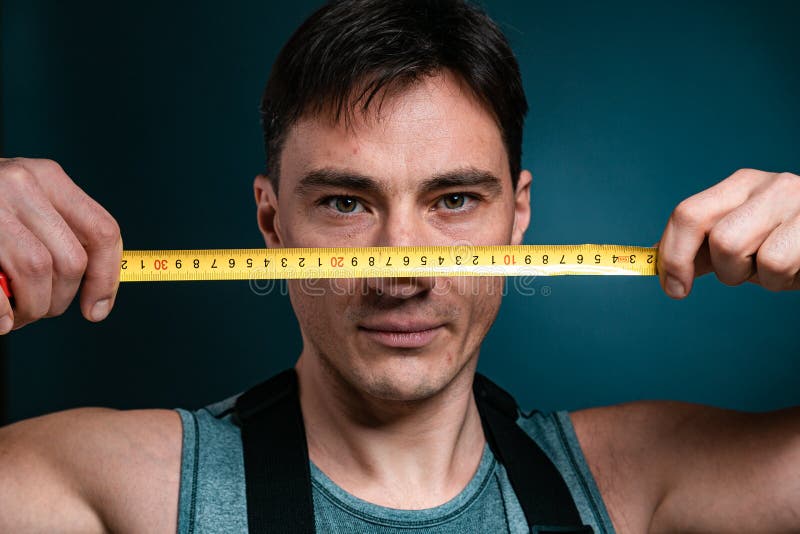 A Worker Holds a Tape Measure in Front of His Face Stock Image - Image ...