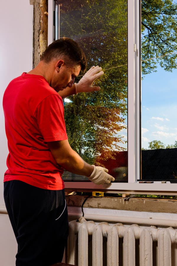 The Worker Inserts Glass into the Window Frame, Triple Glazing of the ...