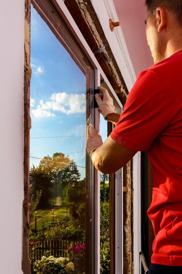 The Worker Inserts Glass into the Window Frame, Triple Glazing of the ...