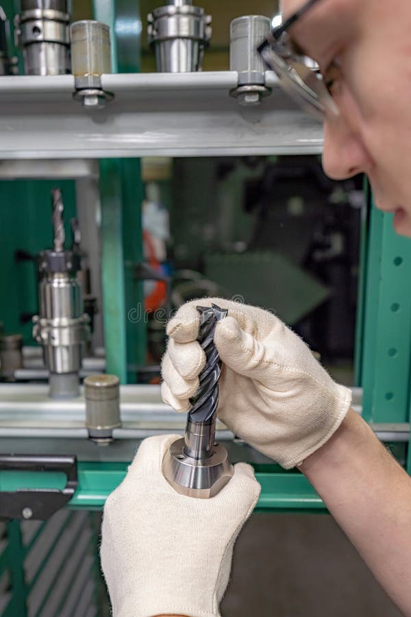 A Worker Inspects and Selects a Cutter from a Rack To Use on a CNC ...
