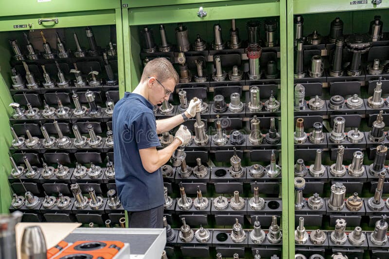 A Worker Inspects and Selects a Cutter from a Rack To Use on a CNC ...