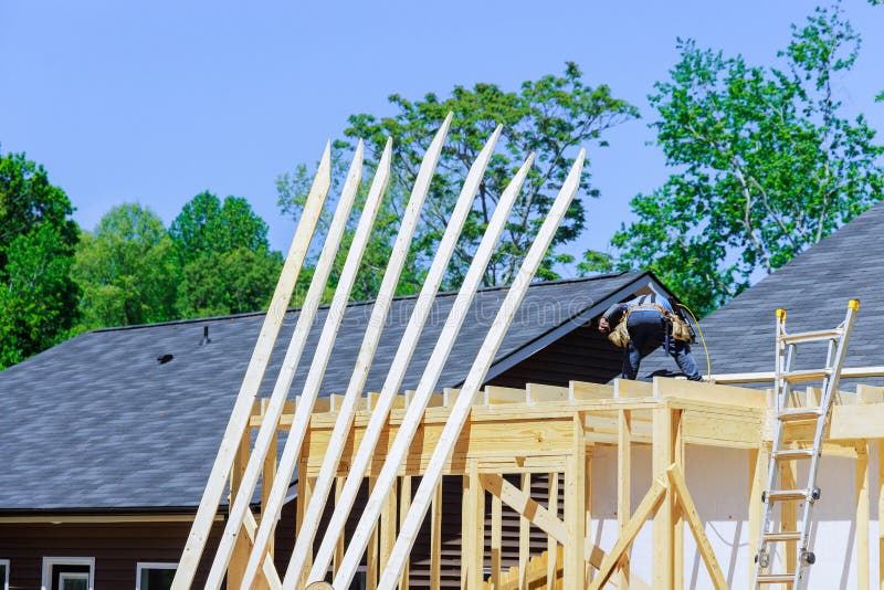 Worker Installing Beams Using an Air Hammer while Nailing Wooden Plank ...